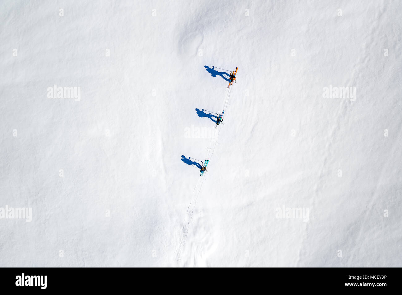 Aerial view of three skiers and their shadows in the Alps, Sportgastein ...