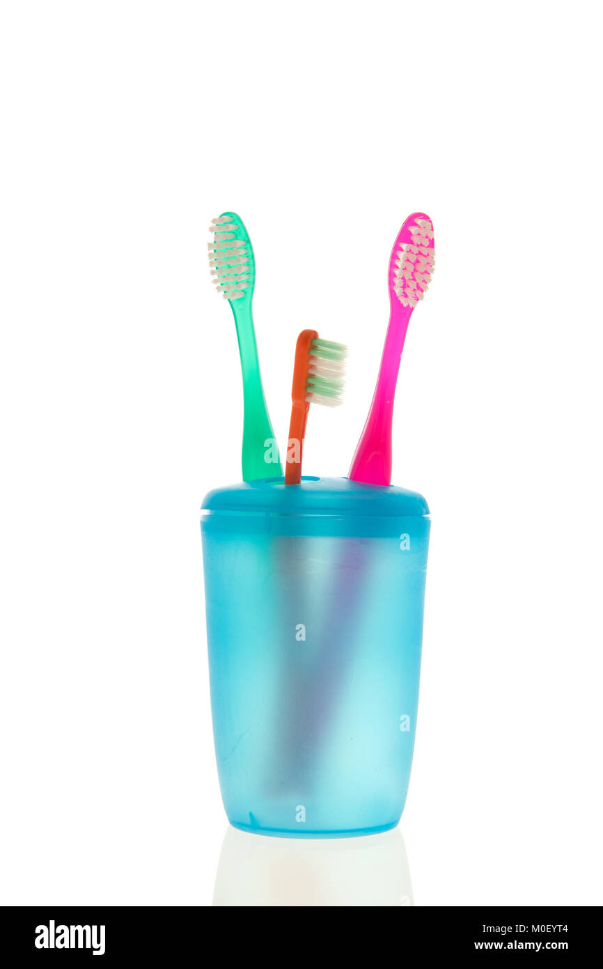 Three dental brushes in blue bathroom mug isolated over white ...