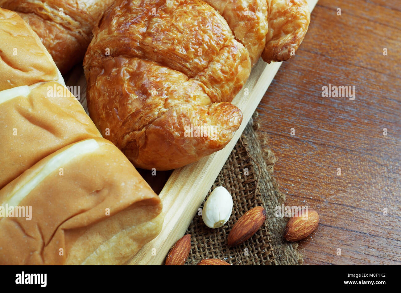 Bread in tray and almonds on wooden floor Stock Photo - Alamy