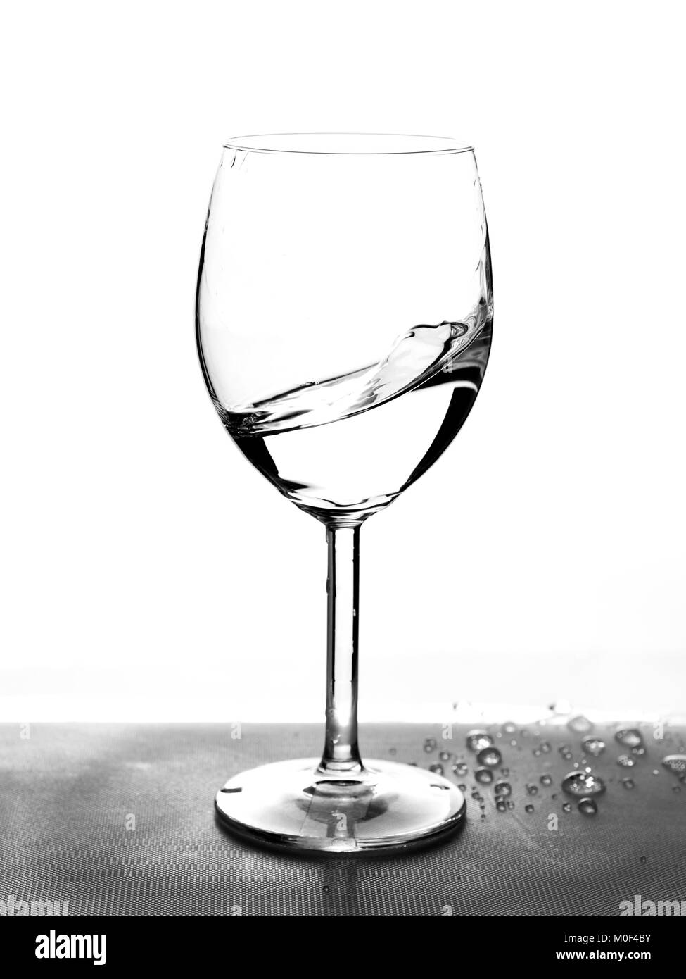 Half empty glass with water splashes in motion on white background ...