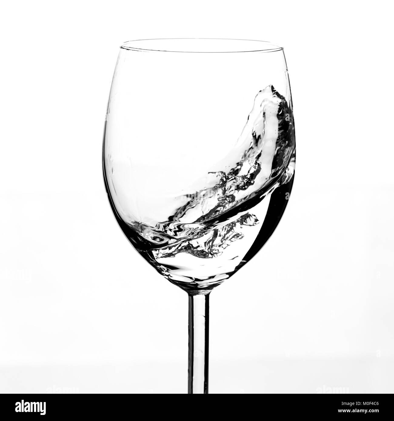 Half empty glass with water splashes in motion on white background ...