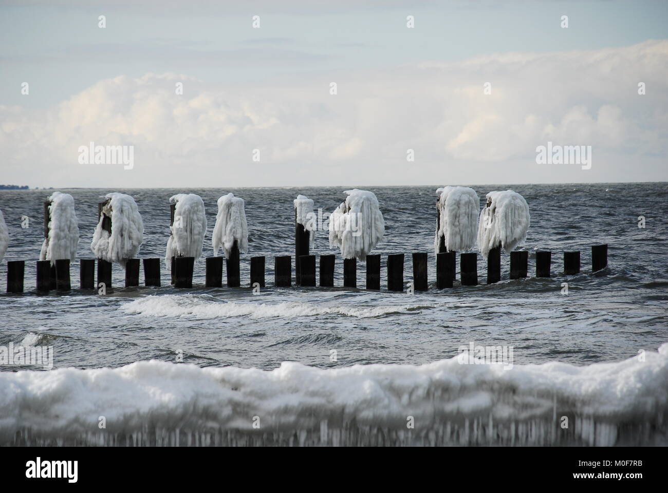 Accumulation of ice on groynes in front of a magnificent cloud ...