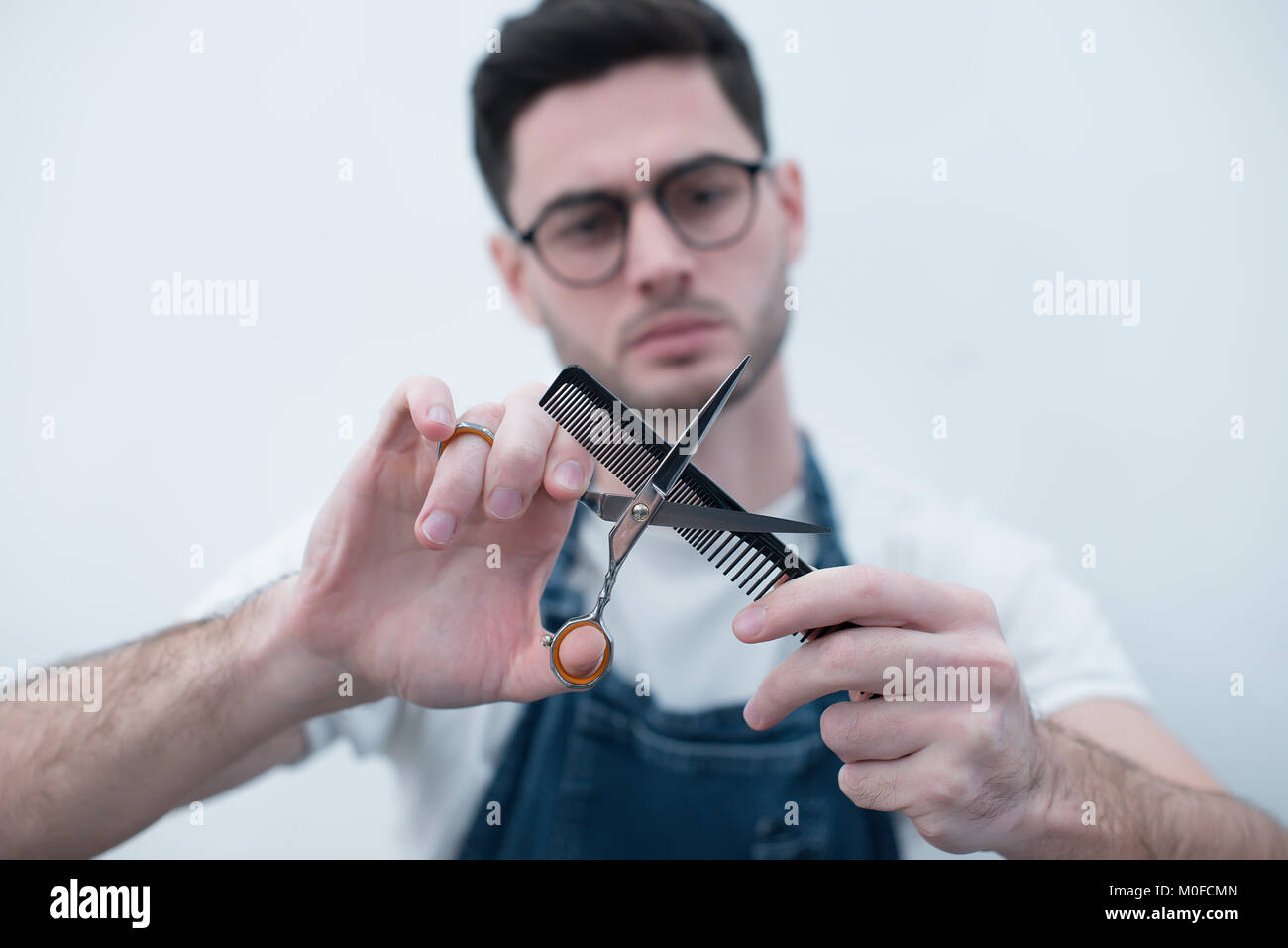 Barber holds the comb and scissors on his arms outstretched against the ...