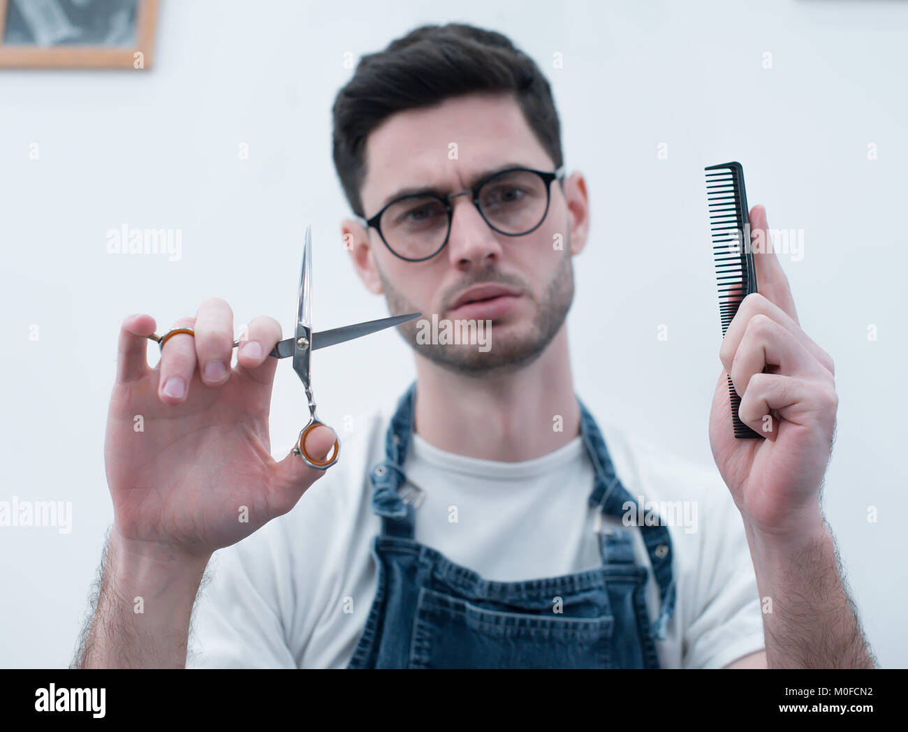 Barber holds the comb and scissors on his arms outstretched against the ...