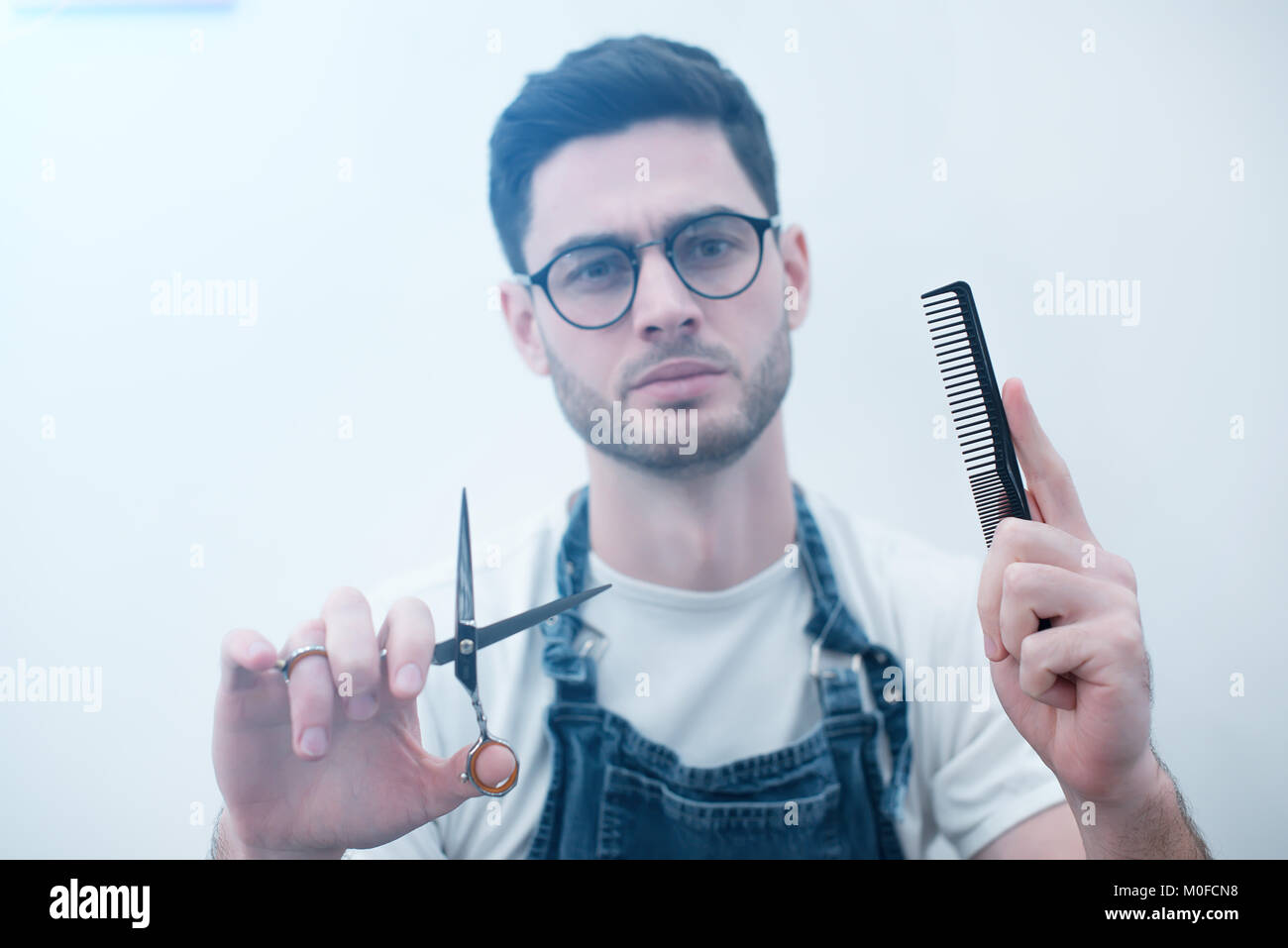 Barber holds the comb and scissors on his arms outstretched against the ...
