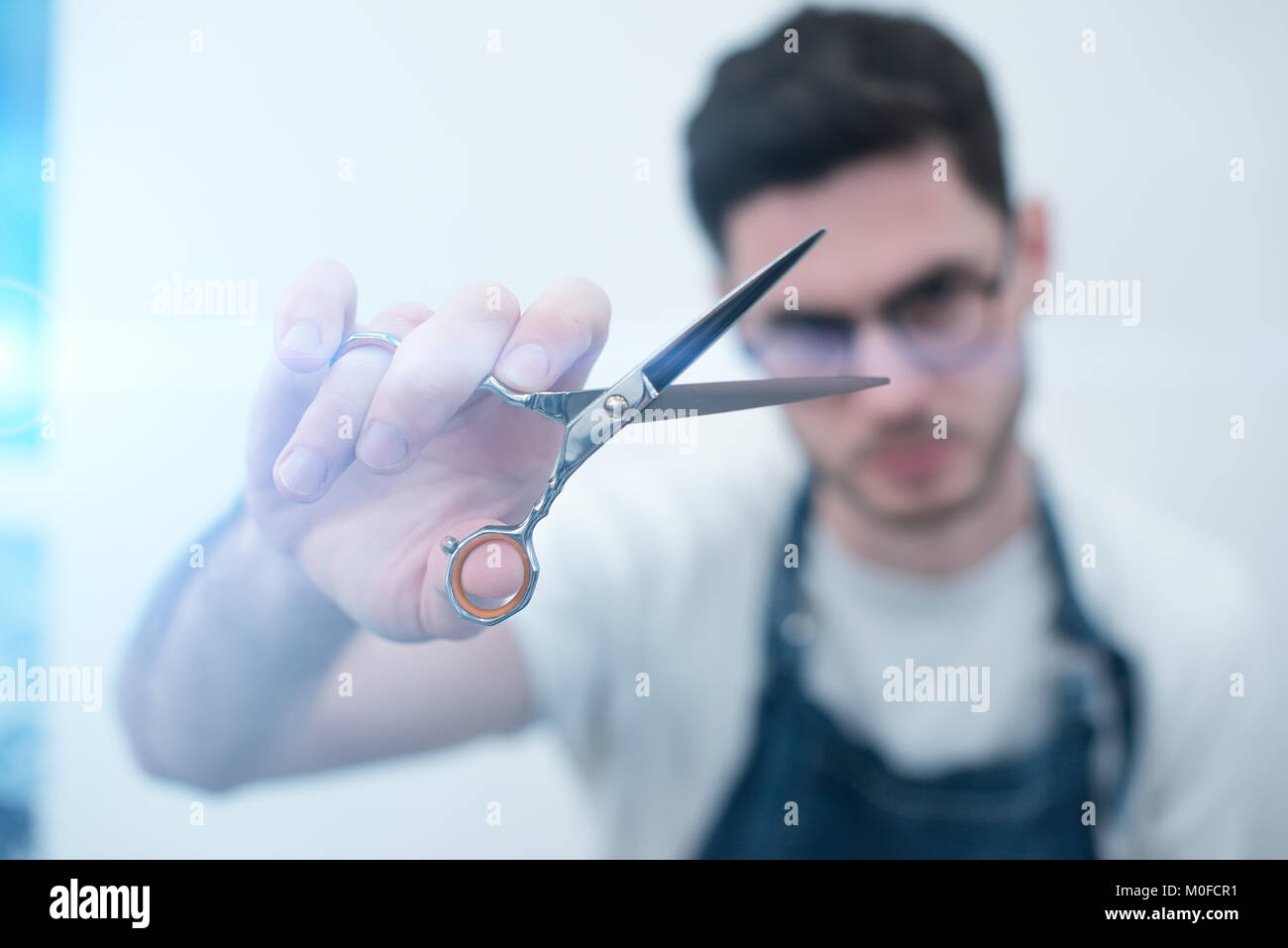 Barber keeps the scissors on his elongated hands against the background ...