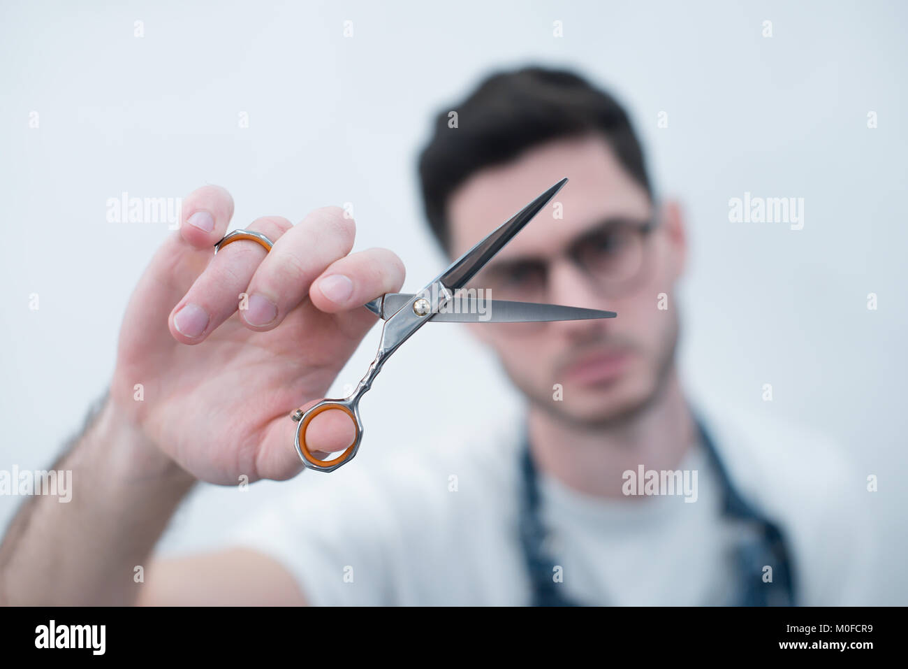 Barber keeps the scissors on his elongated hands against the background ...