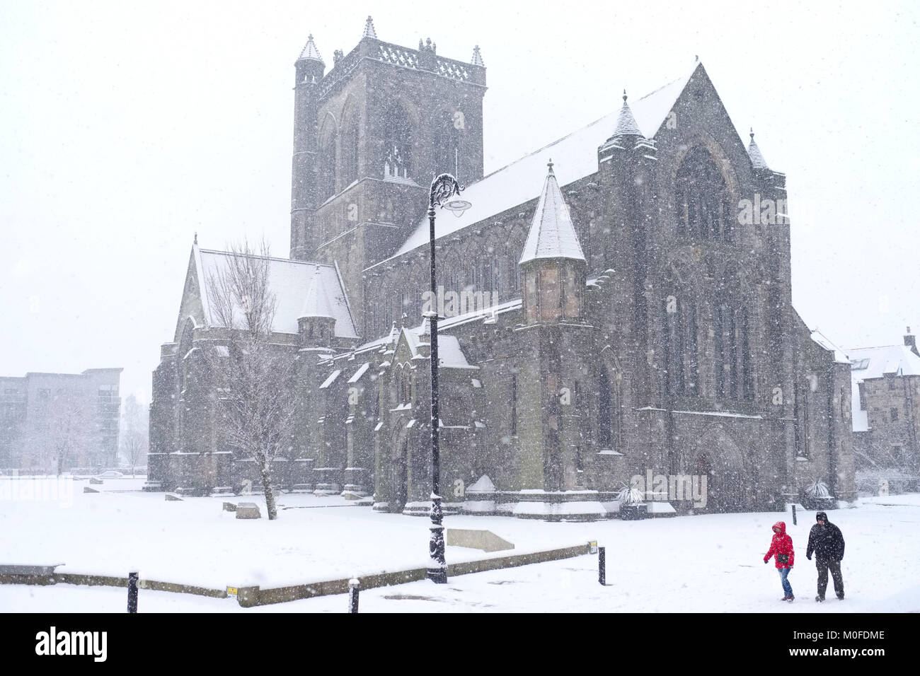 Couple in deep snow Paisley Abbey during harsh cold unexpected winter ...