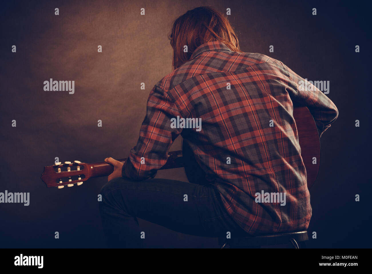 Rear view of young musican. Back of male guitarist playing on his ...