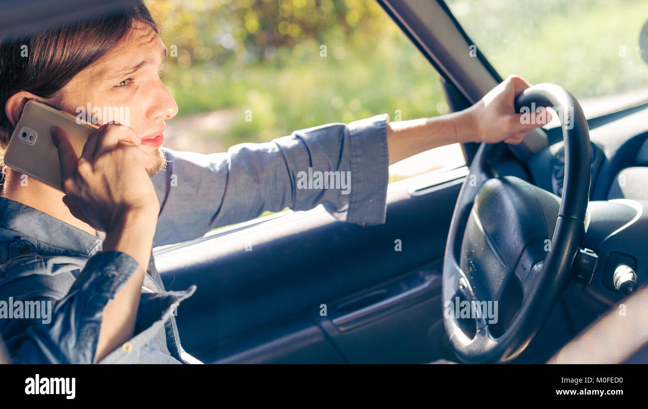 Talking while drive, danger fresh driver concept. Young man driving car ...