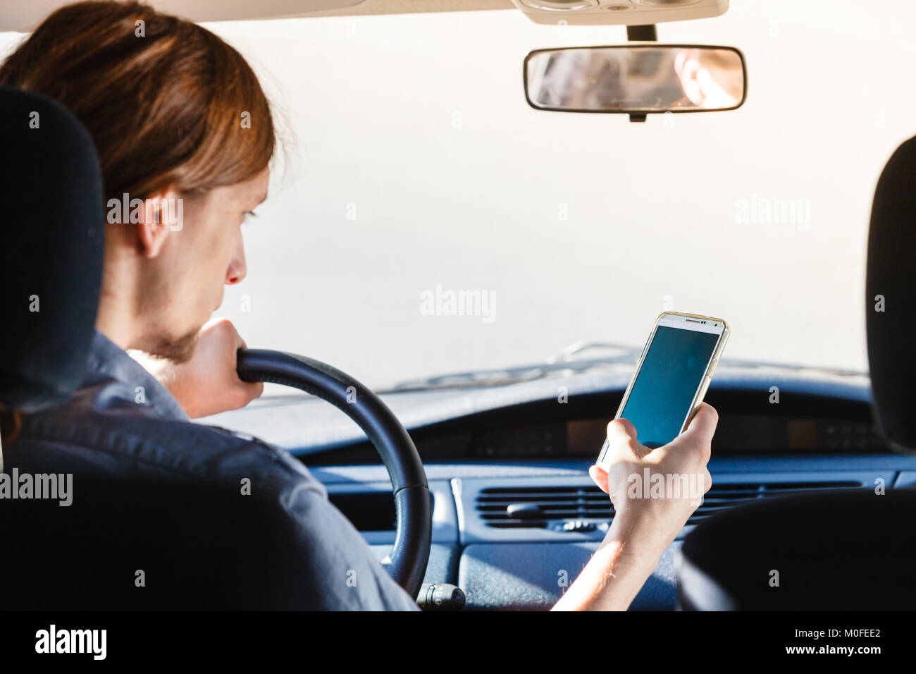 Modern technology concept. Man using mobile phone while driving car ...