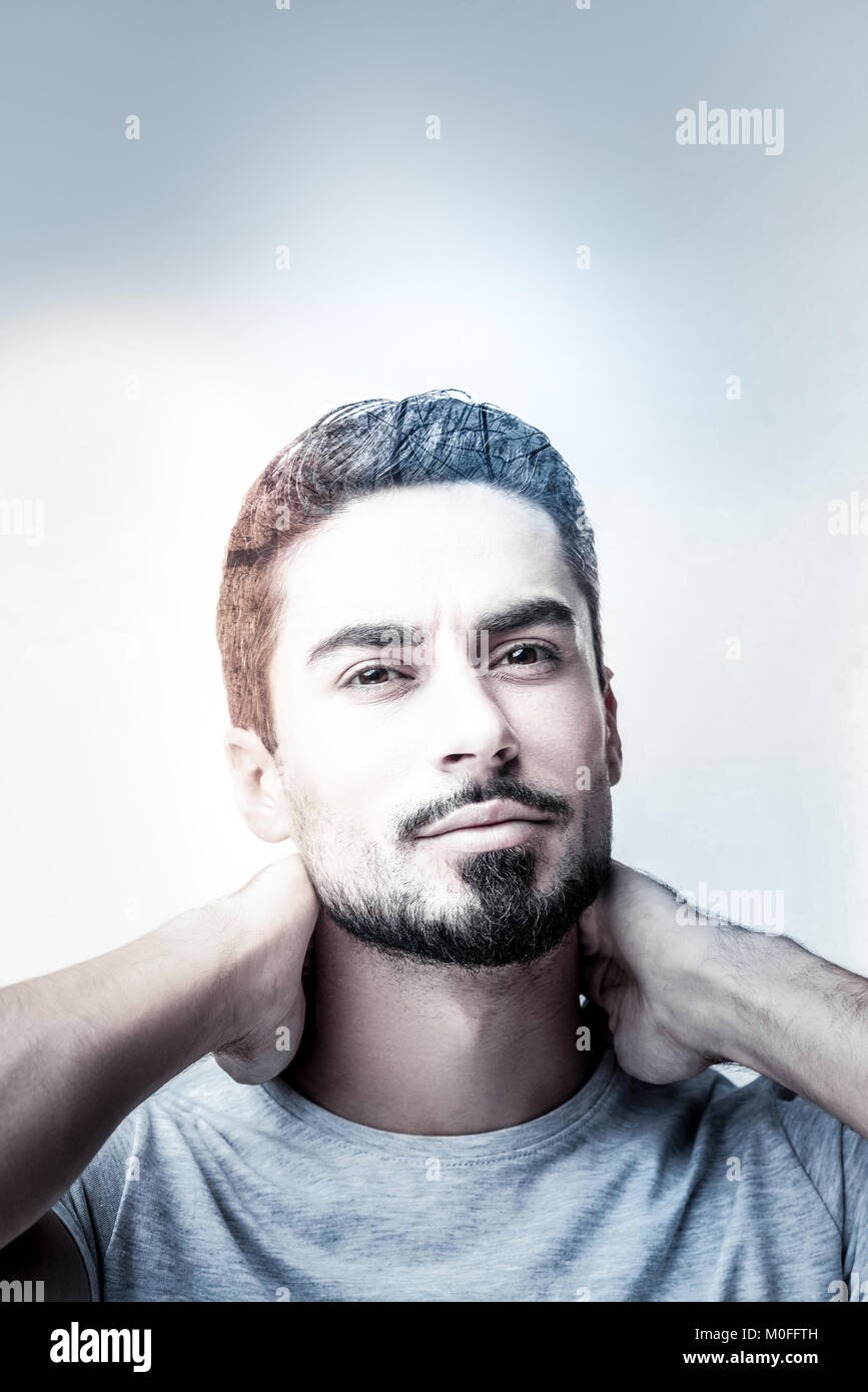 Handsome brunette man touching his neck Stock Photo - Alamy