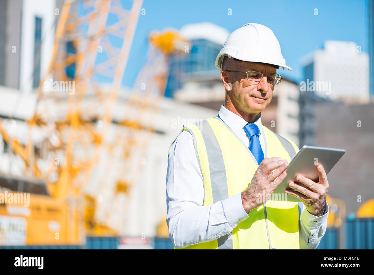 Construction manager controlling building site and tablet device in his ...
