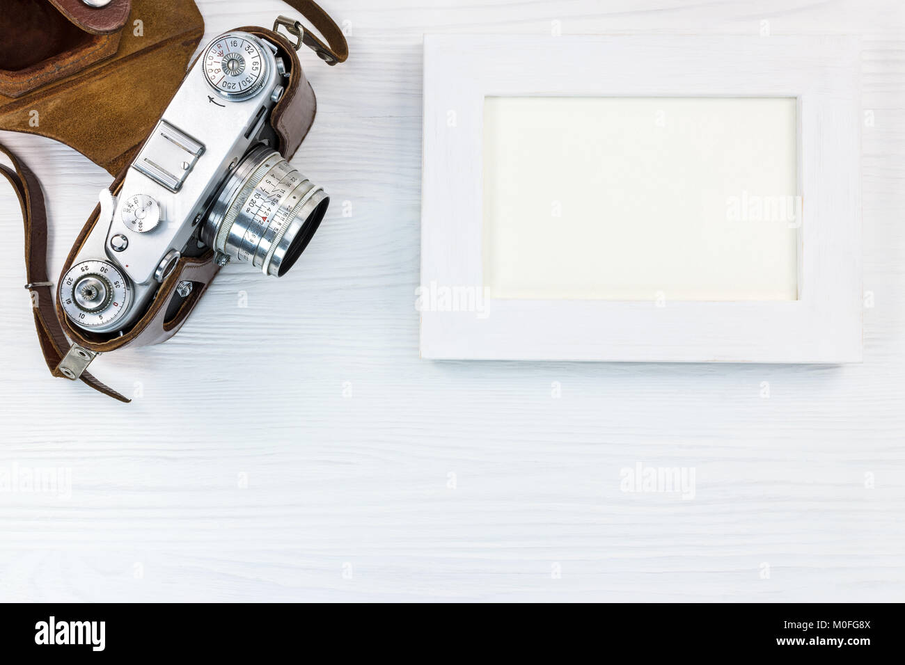 vintage classic film camera in leather cover and white photo frame on ...