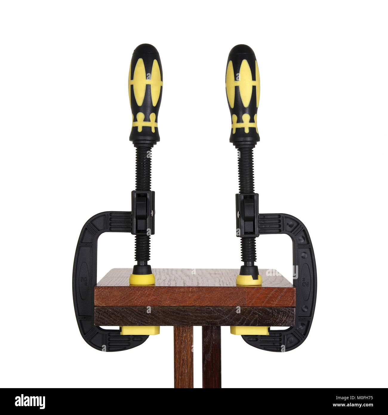 clamps of yellow color hold two wooden bars on a white background. Use ...