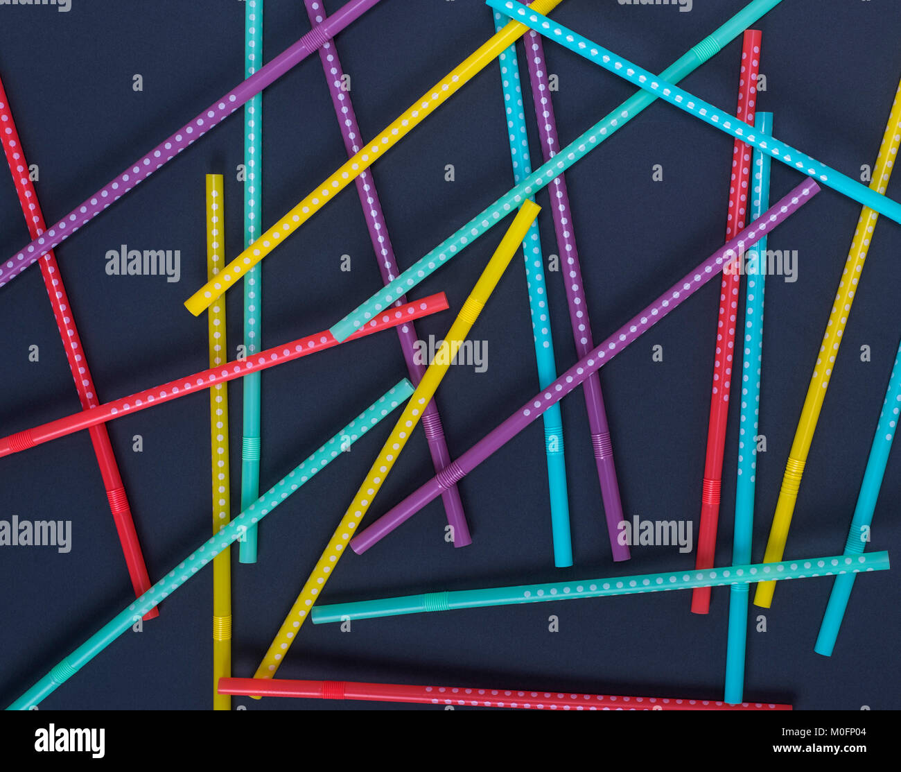 multi-colored plastic tubes in a white polka-dot for drinks are ...