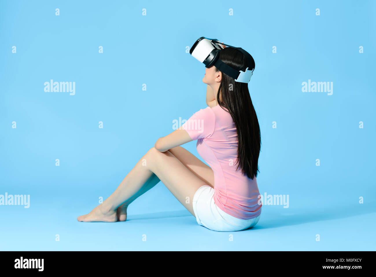 pretty beauty woman wearing virtual reality goggles sitting on blue ...