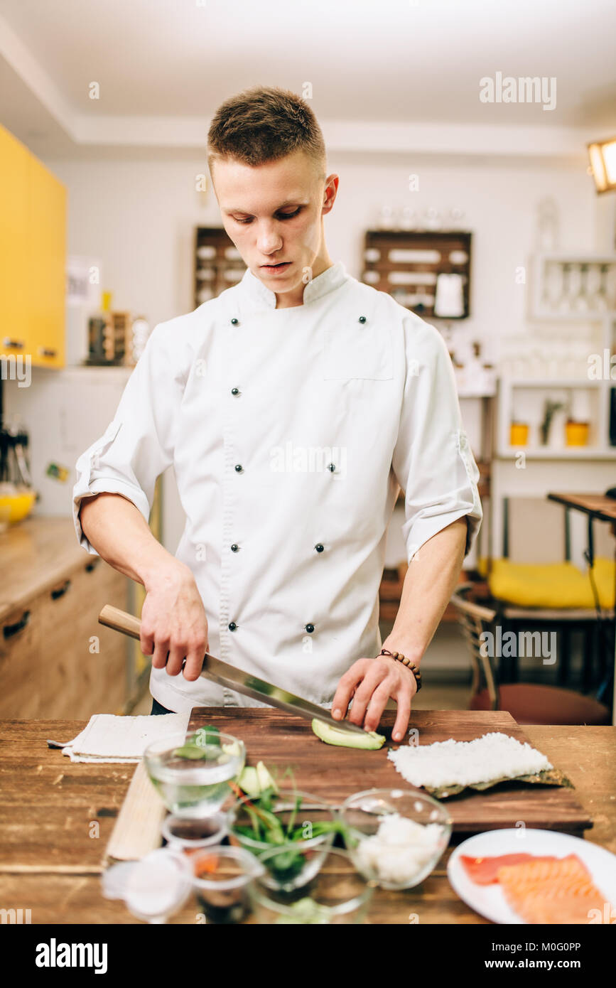 Male cook making sushi rolls on the kitchen. Traditional japanese food ...