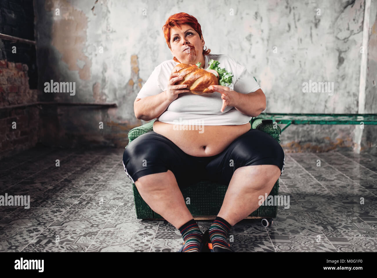 Fat woman sits in a chair and eats sandwich, bulimic and overweight ...