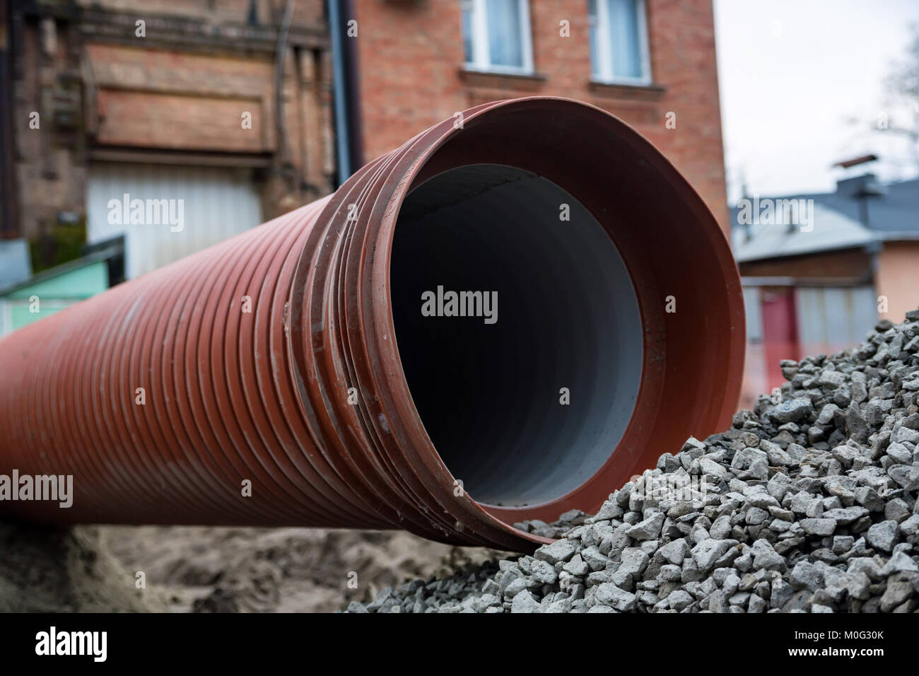 Close up red corrugated pipe lying on pile of crushed stone outdoors at ...