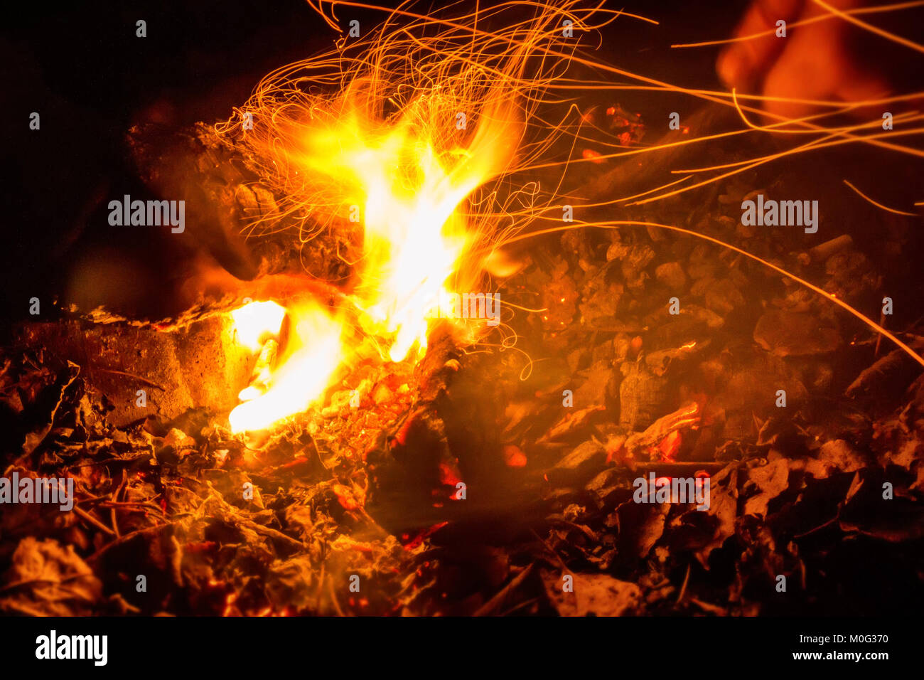 Close up picture of man's hand touching fire with stick taken with slow ...