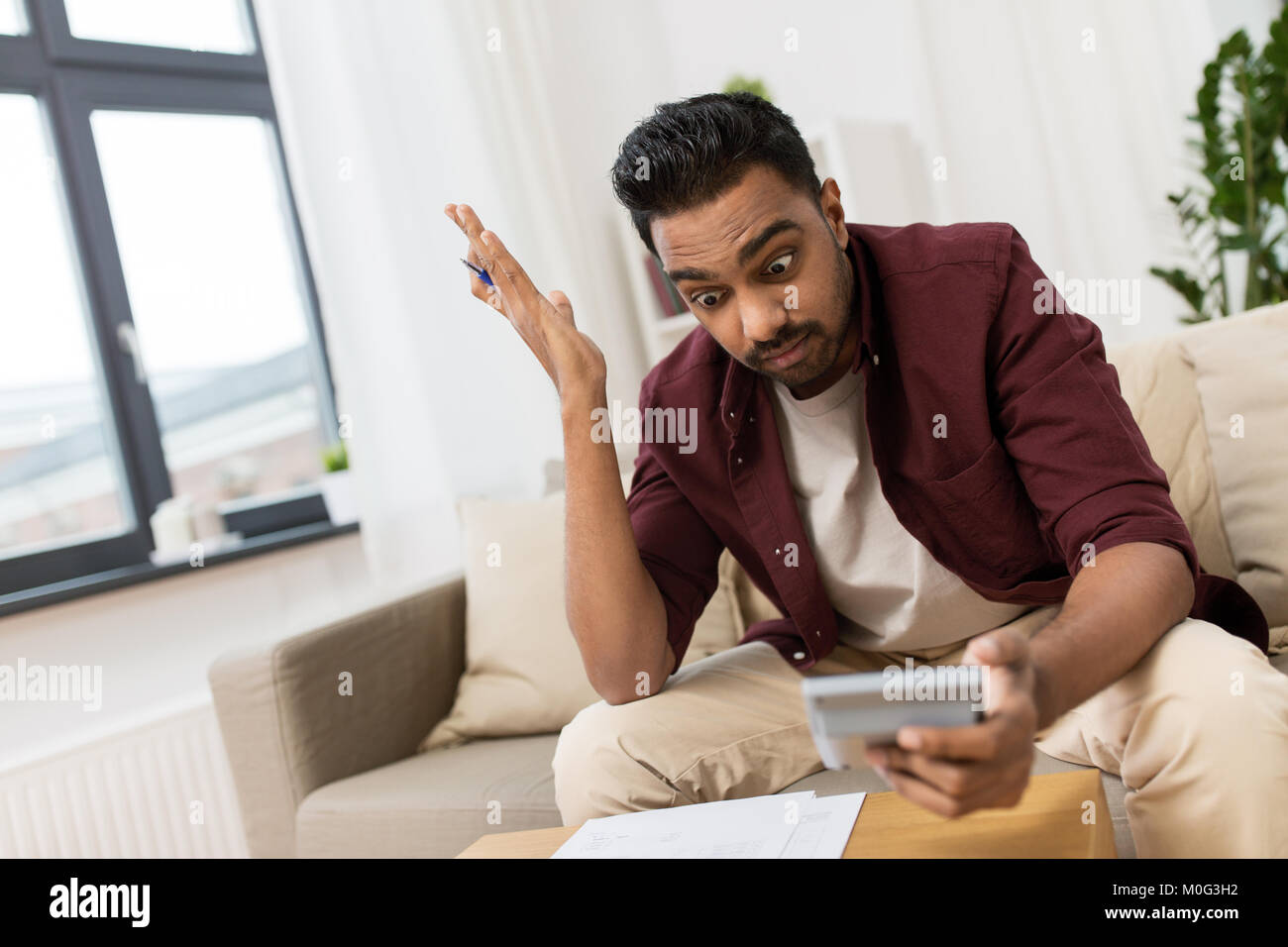 confused man with papers and calculator at home Stock Photo - Alamy