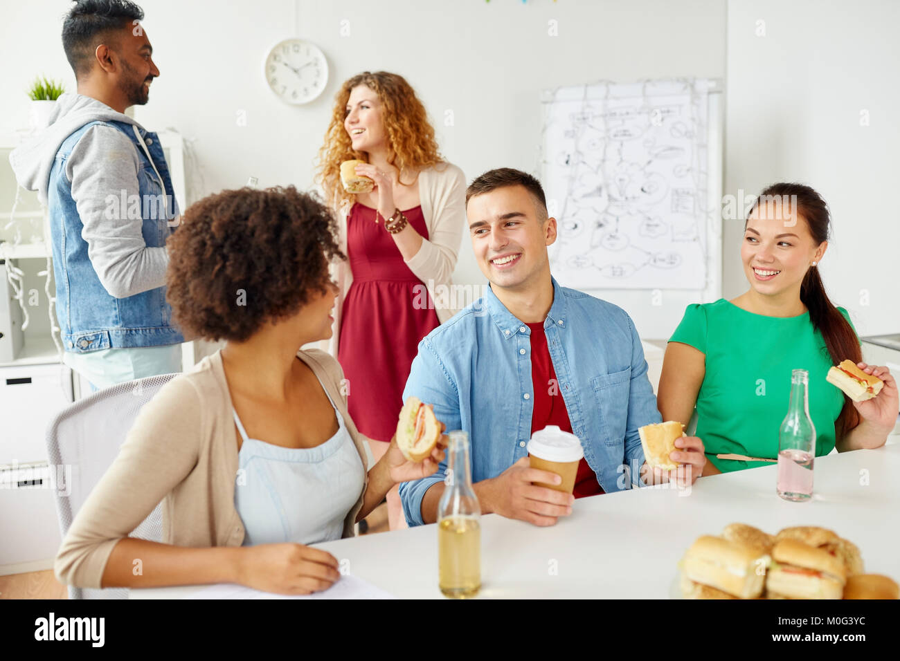 happy friends or team eating at office Stock Photo - Alamy