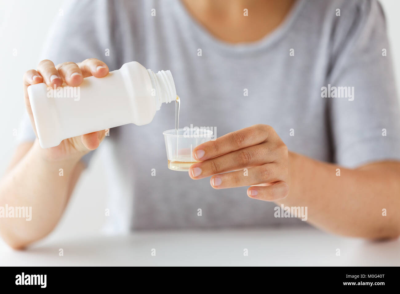 woman pouring syrup from bottle to medicine cup Stock Photo - Alamy