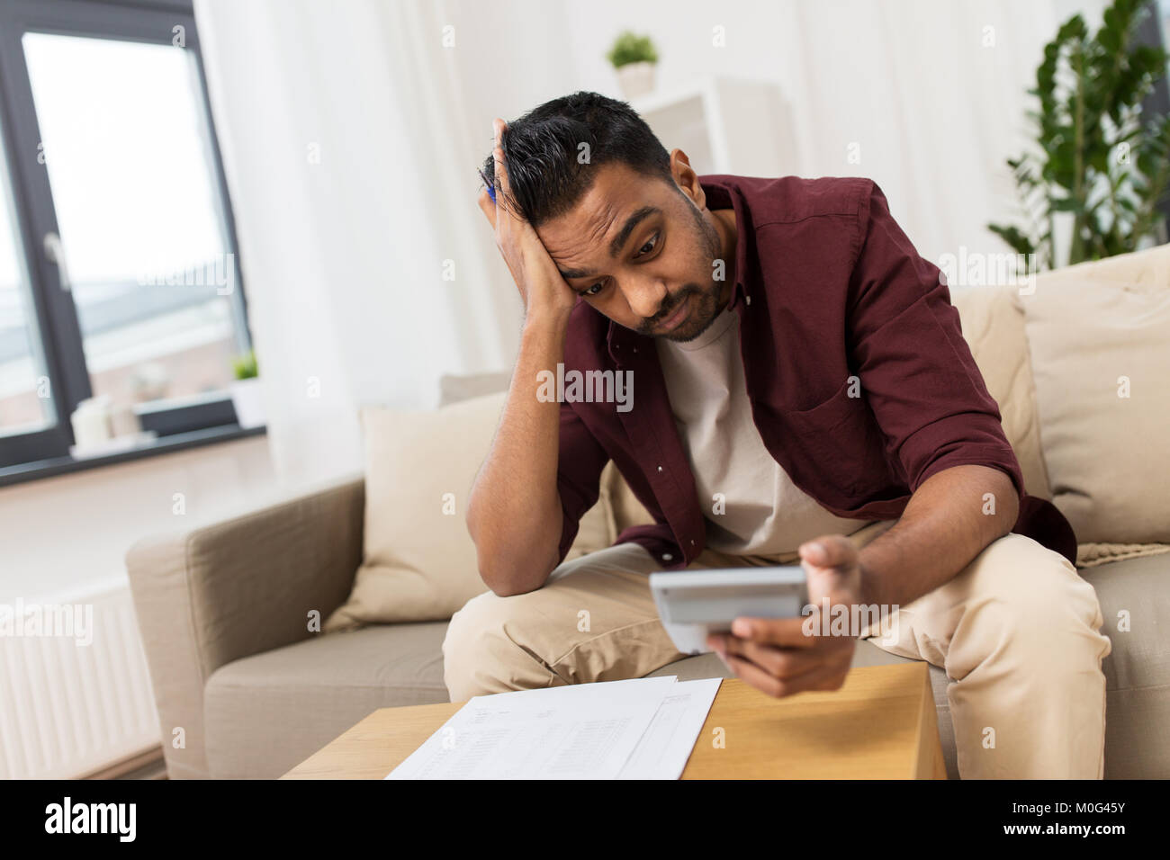 confused man with papers and calculator at home Stock Photo - Alamy