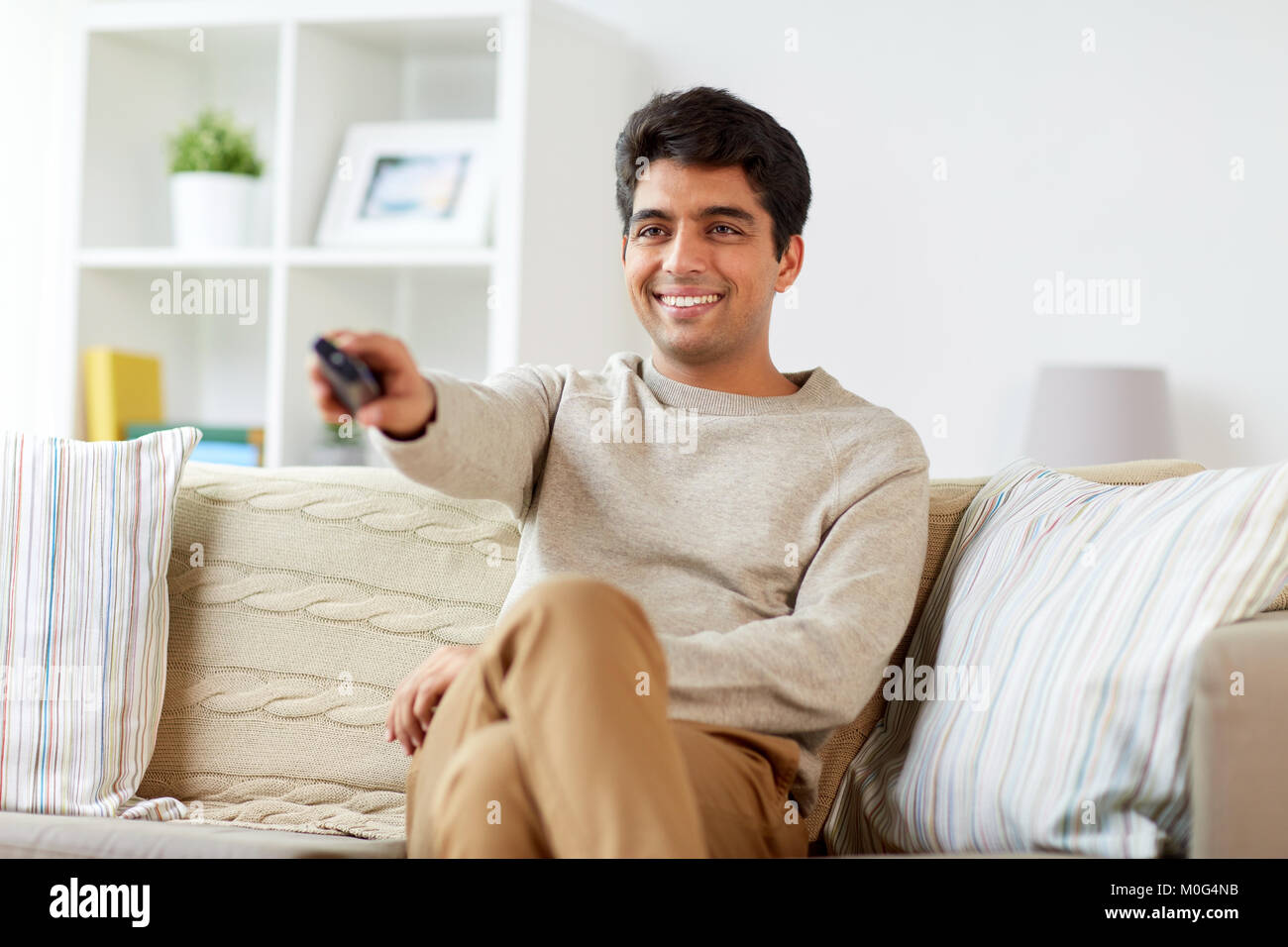 man with remote control watching tv at home Stock Photo - Alamy