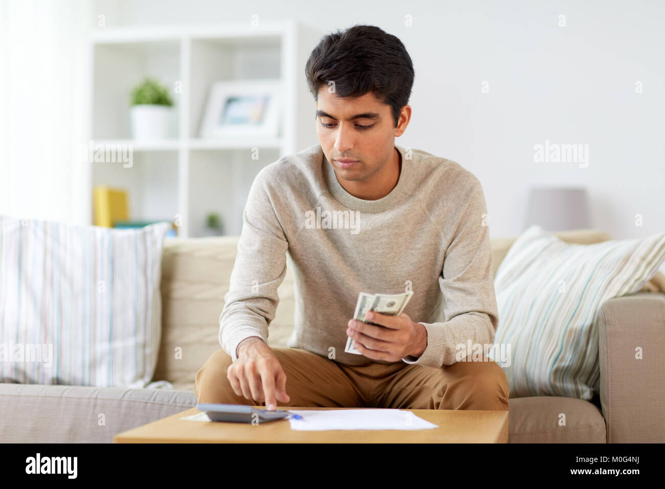 man with calculator counting money at home Stock Photo - Alamy
