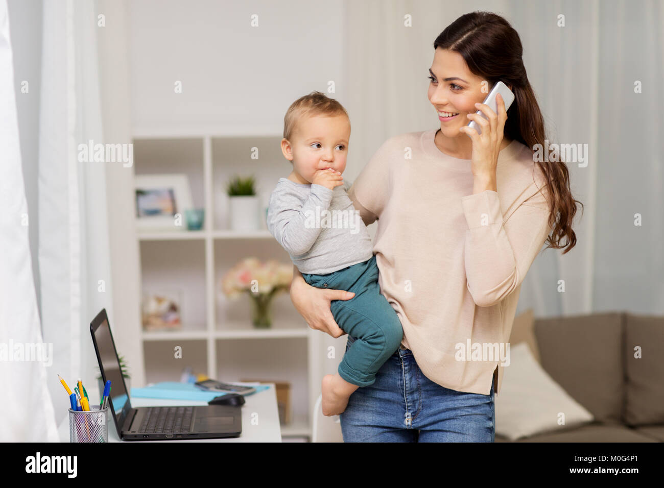 mother with baby calling on smartphone at home Stock Photo - Alamy