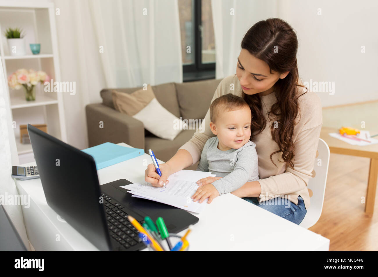 happy mother with baby and papers working at home Stock Photo - Alamy