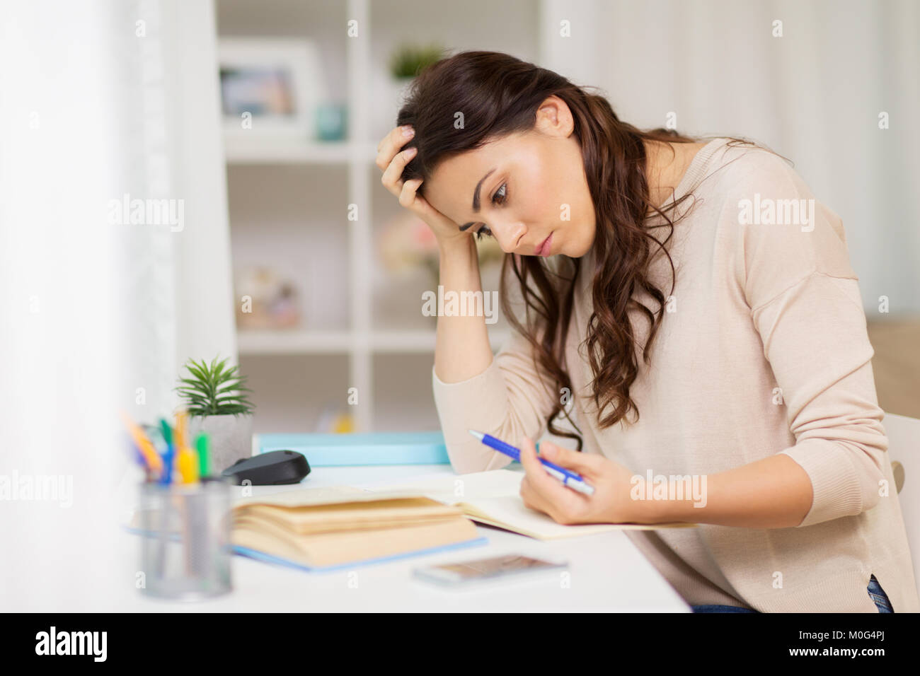 tired female student with book learning at home Stock Photo - Alamy