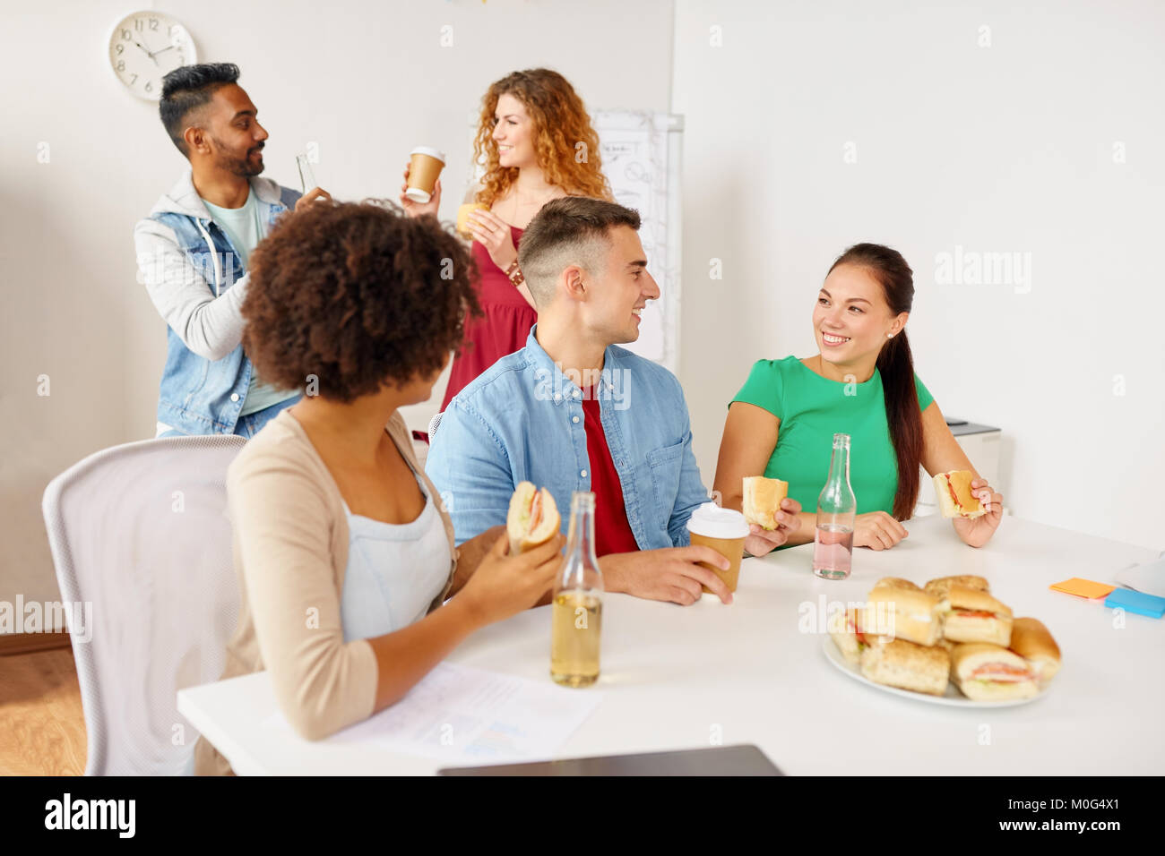 happy friends or team eating at office Stock Photo - Alamy