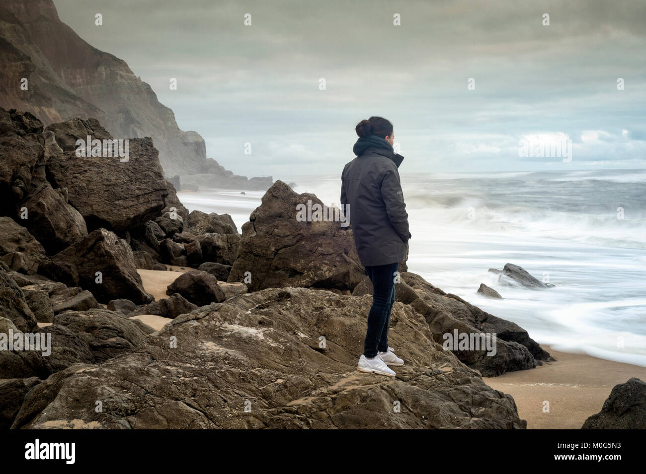 woman hiker standing on rocks looking out over the ocean Stock Photo ...