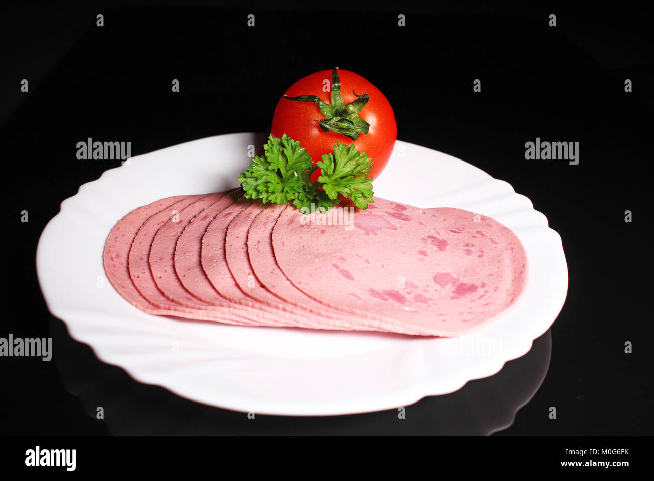 Round ham. Sliced pink ham meat on black reflective studio background ...