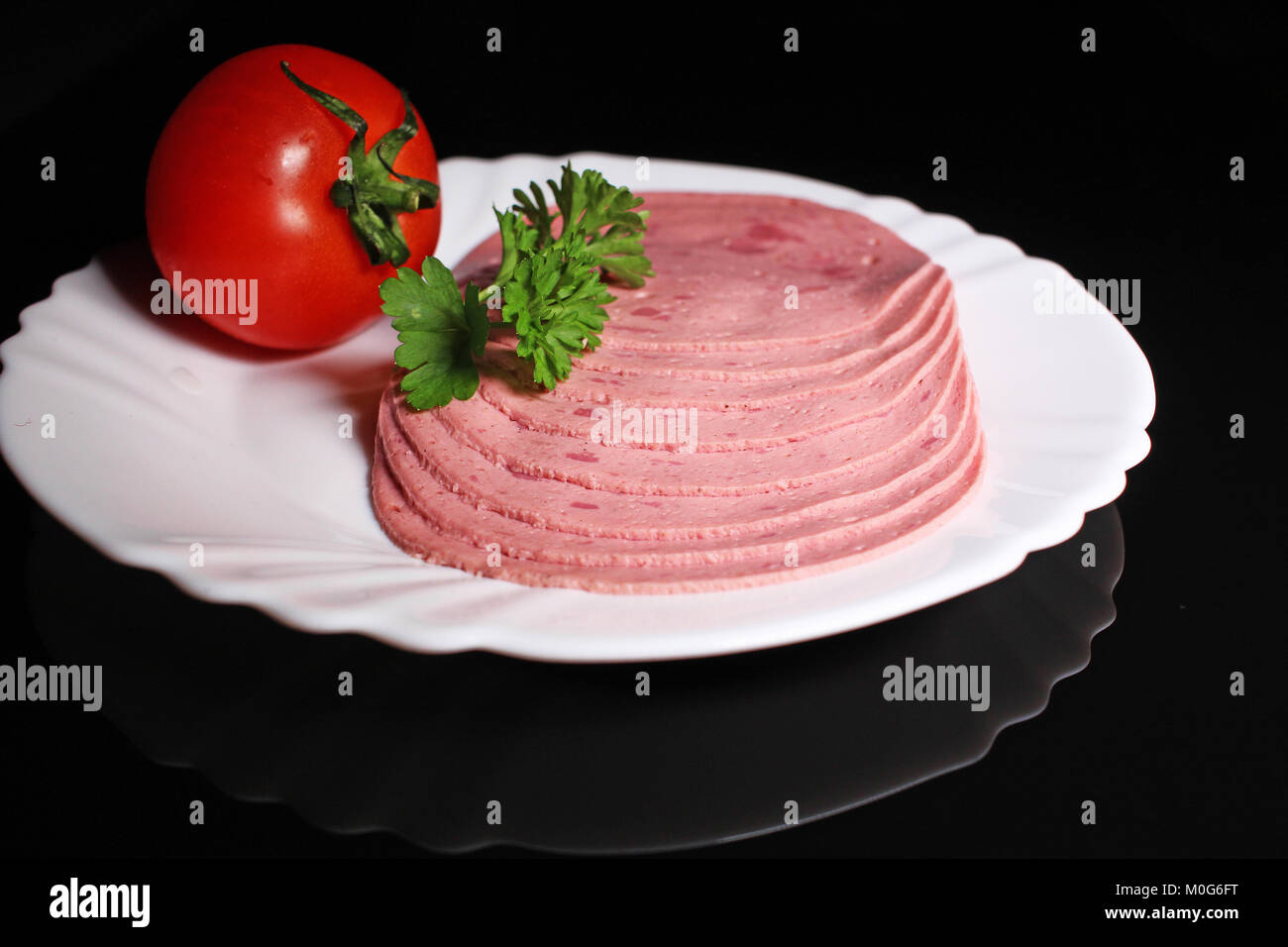 Round ham. Sliced pink ham meat on black reflective studio background ...