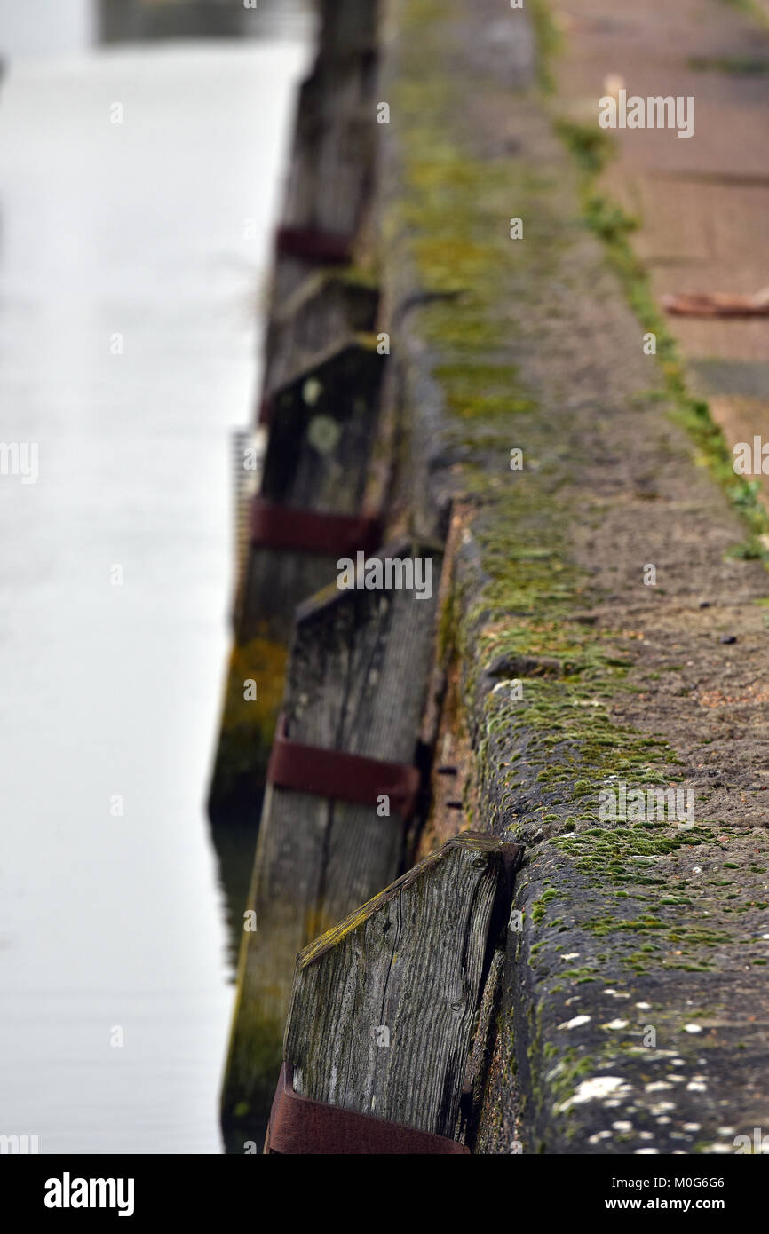 An old unused harbour or dock wall with moss and seaweed growing on the ...