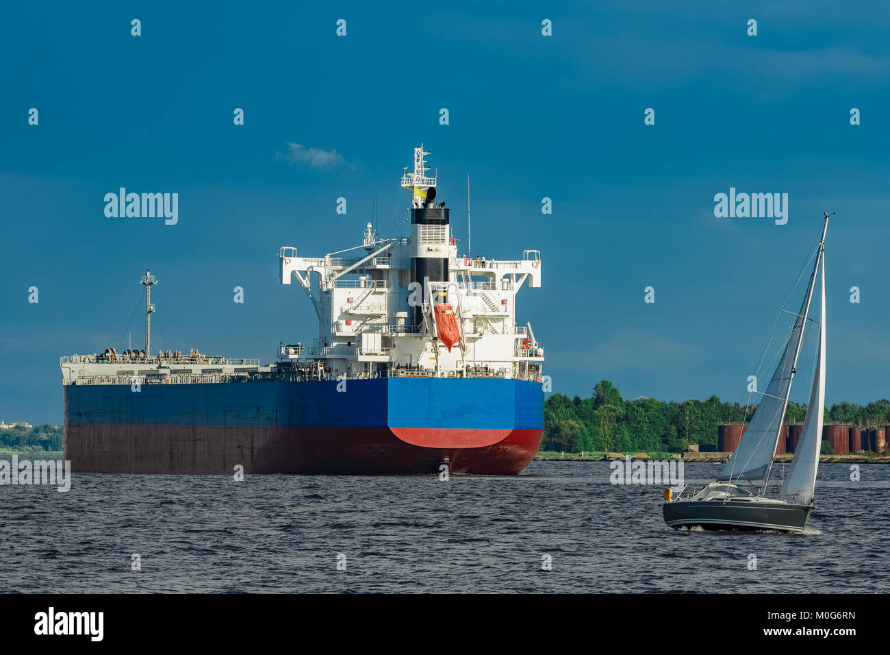 Merchandise import. Large blue cargo ship moving to Riga port Stock ...