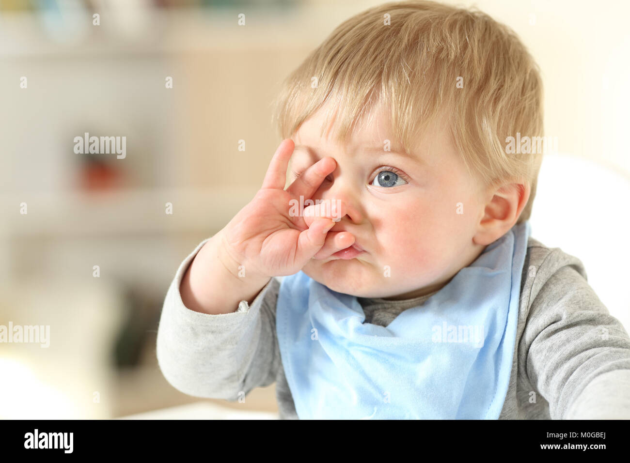 Portrait of a cute baby grimacing with a hand on the face at home Stock ...