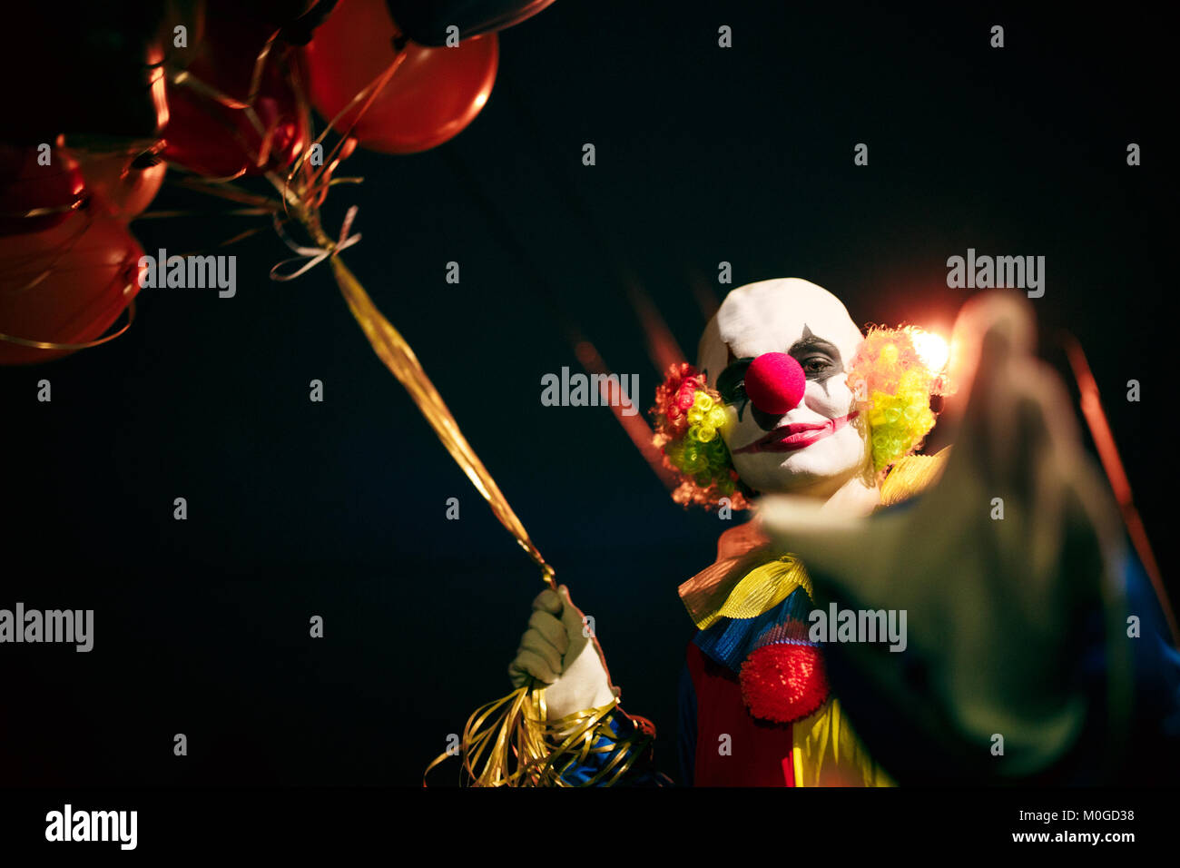 Picture of smiling clown with balloons stretching out hand Stock Photo ...