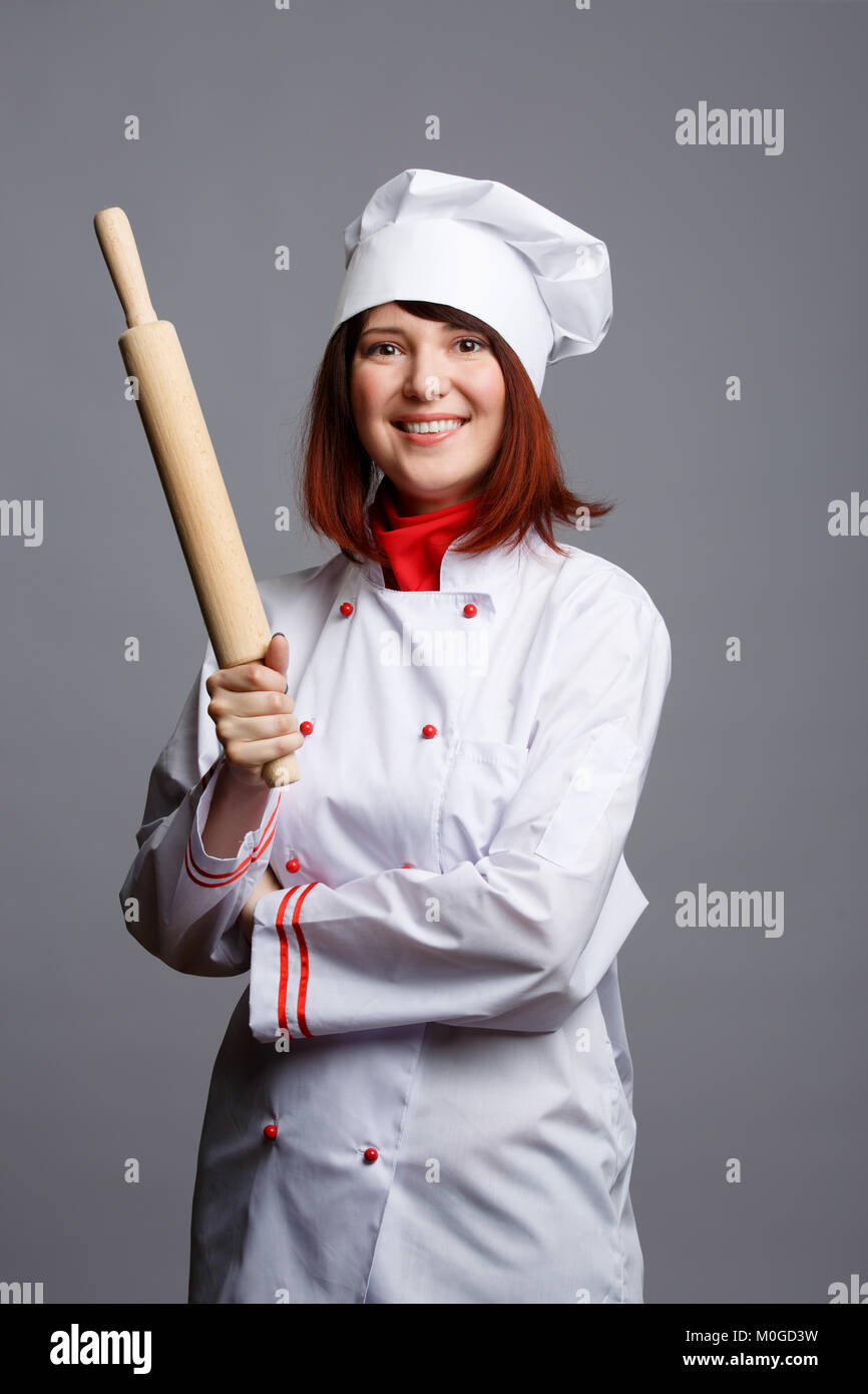Picture of woman cook in white robe and cap with rolling pin in hands ...