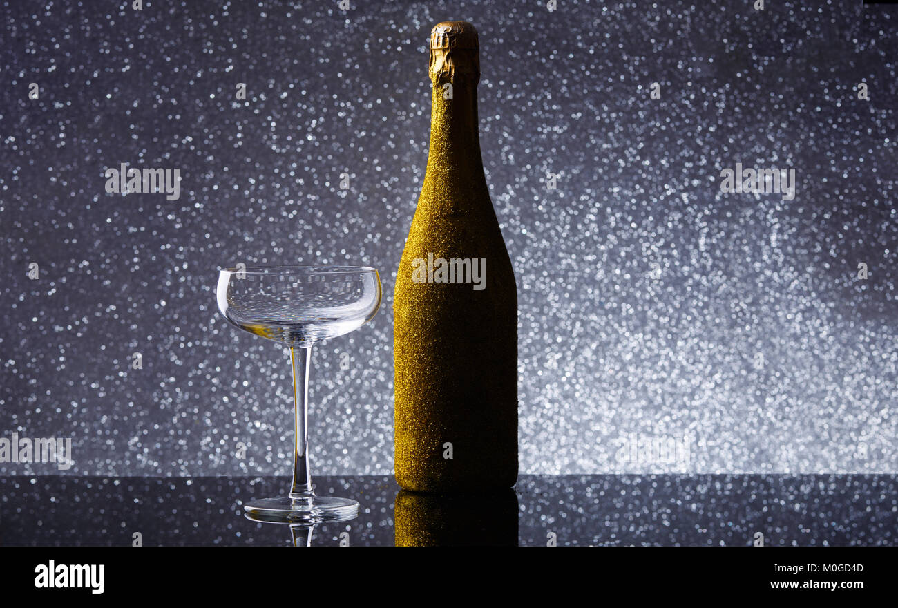 Image of bottle of champagne in gold wrapper with empty wine glass ...