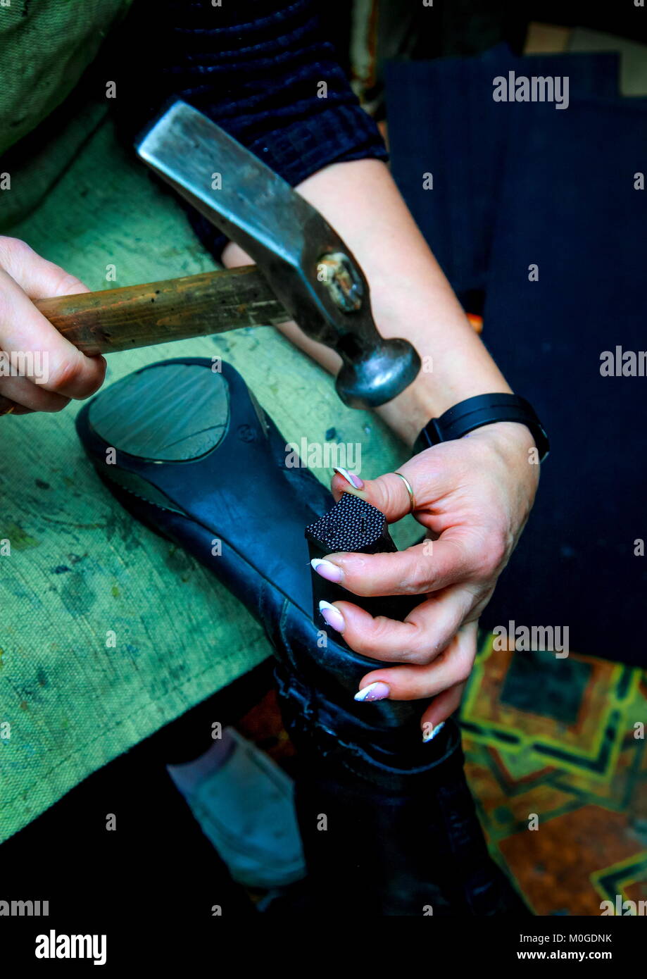 Shoe shop. Female hand of a shoemaker holding a hammer and nailed a ...