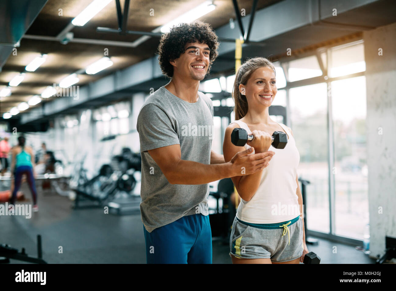 Young beautiful woman doing exercises with personal trainer Stock Photo ...