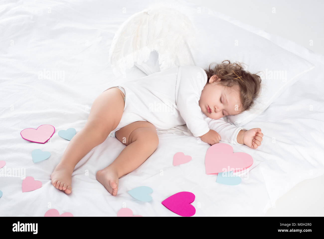 little cherub with wings sleeping on bed with hearts Stock Photo - Alamy
