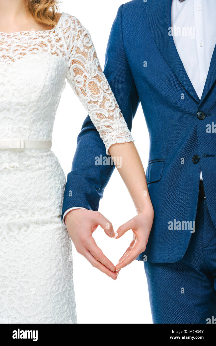 partial view of wedding couple showing heart symbol made of hands ...