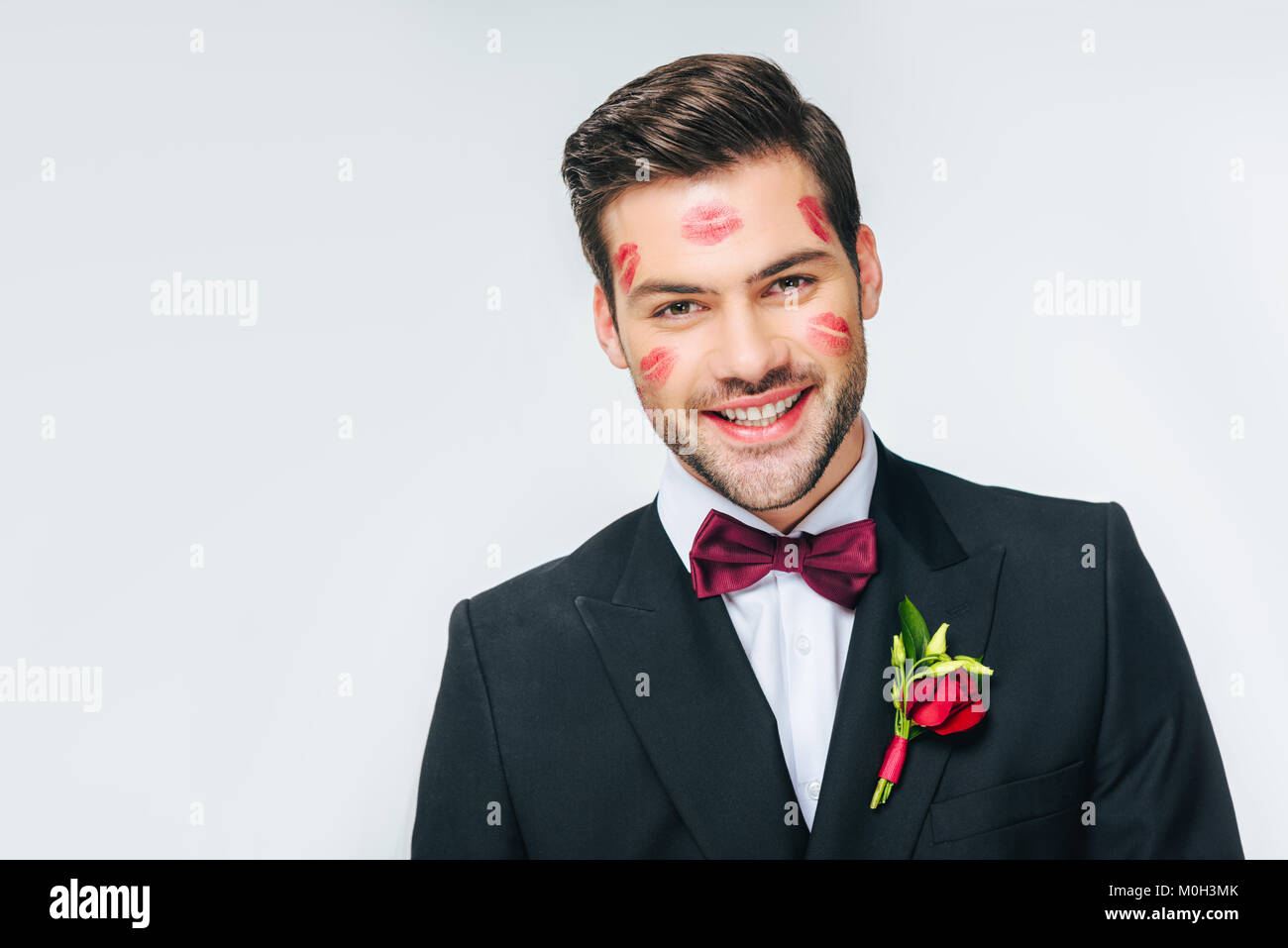 portrait of handsome smiling groom in suit with red lipstick on face ...