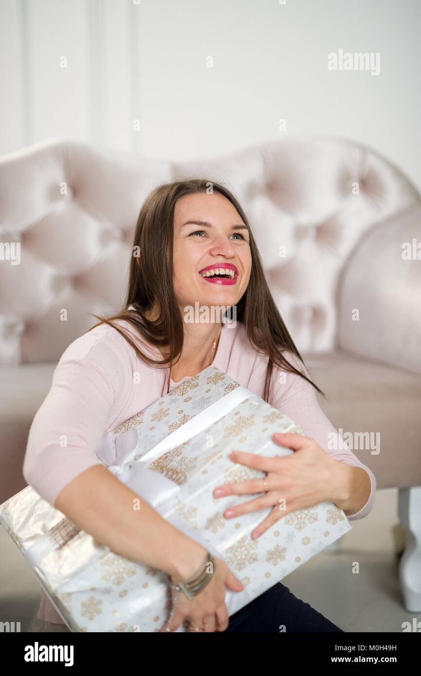 The beautiful young woman embraces a box with a gift. The woman ...